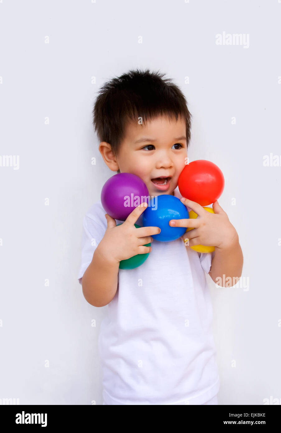 Happy Asian toddler child holding up colorful balls and smiling Stock ...