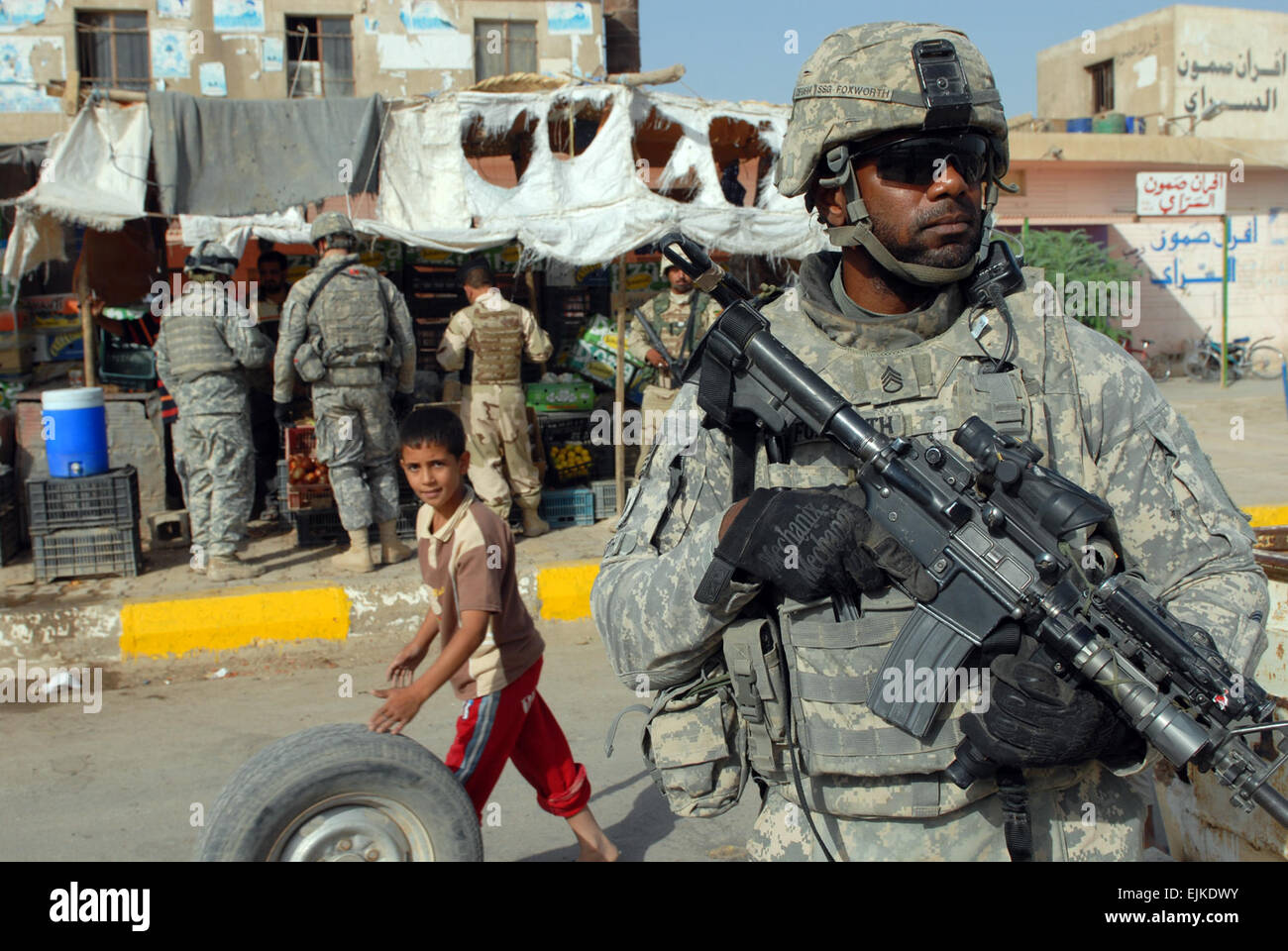 An Iraqi boy rolls a tire behind Staff Sgt. Kevin Foxworth, an infantry ...