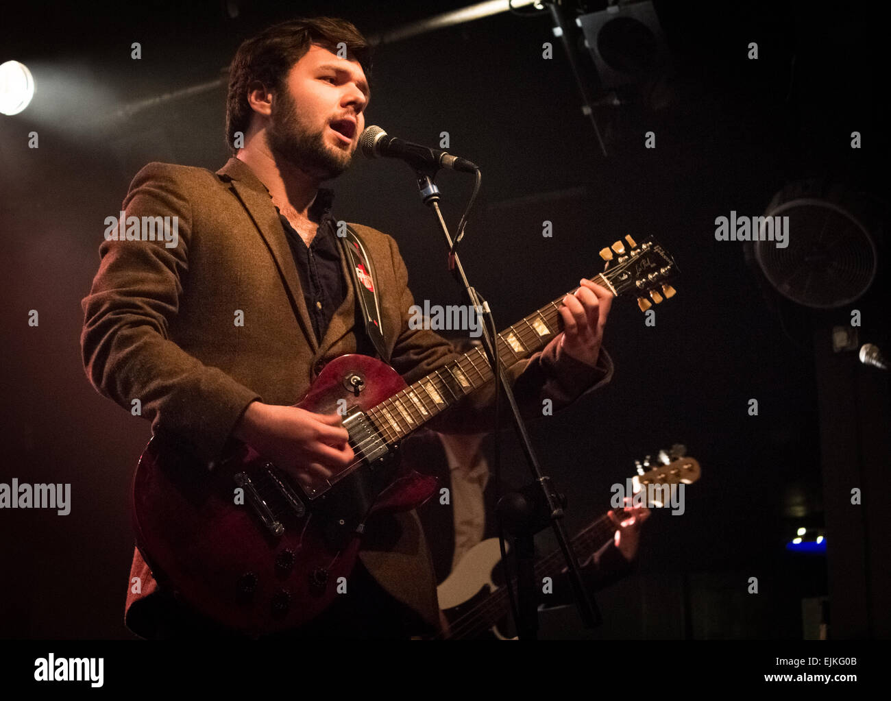 Man in a band singing and playing guitar on a stage at a concert in the ...