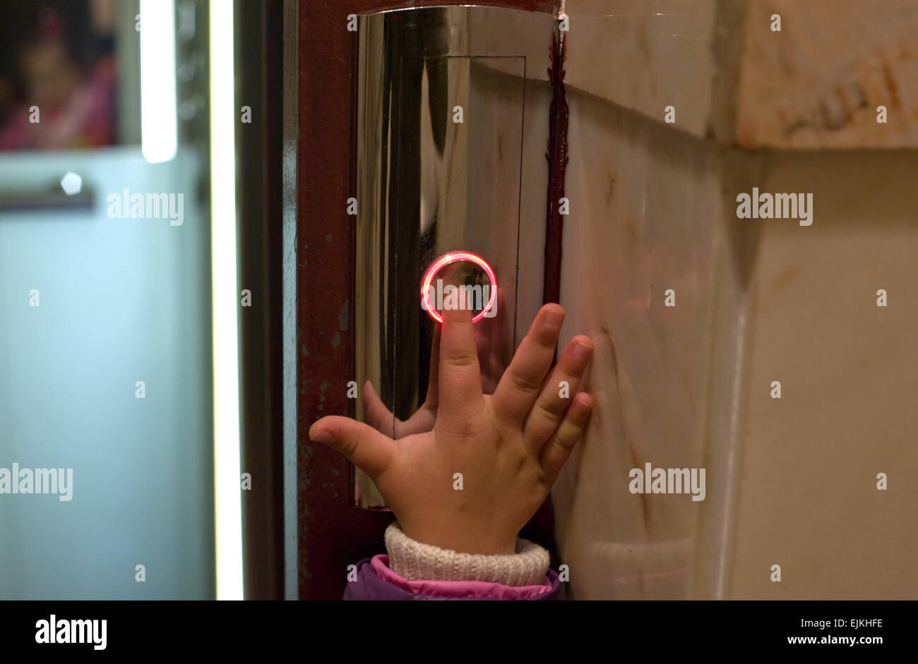 Hand of a toddler in elevator or lift pressing the button to get in ...