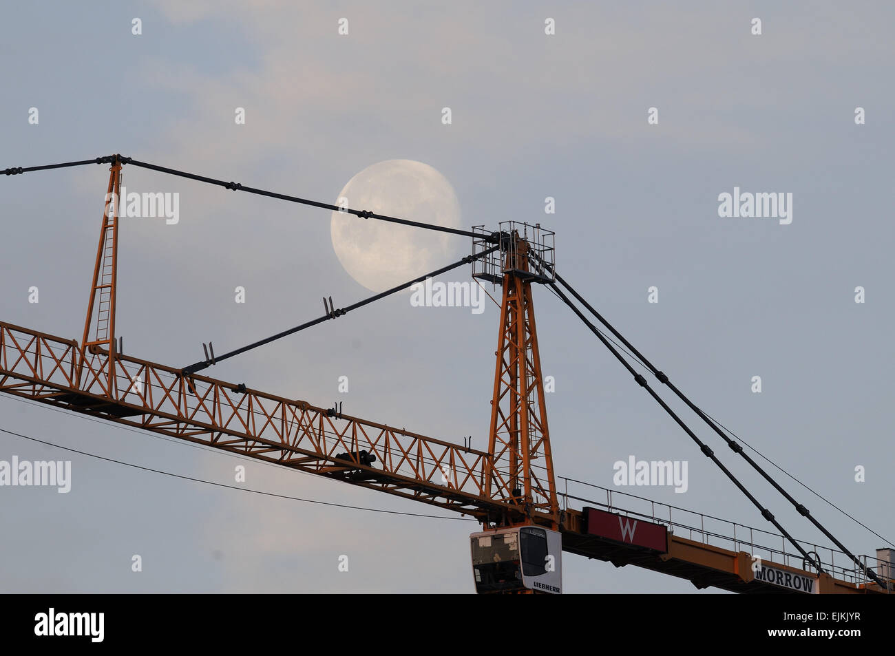 Moon setting behind a crane at sunrise Stock Photo - Alamy