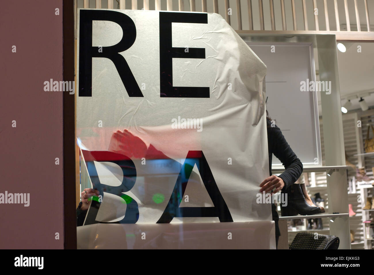Shop workers sticking adverts and banners over shop window at sales ...
