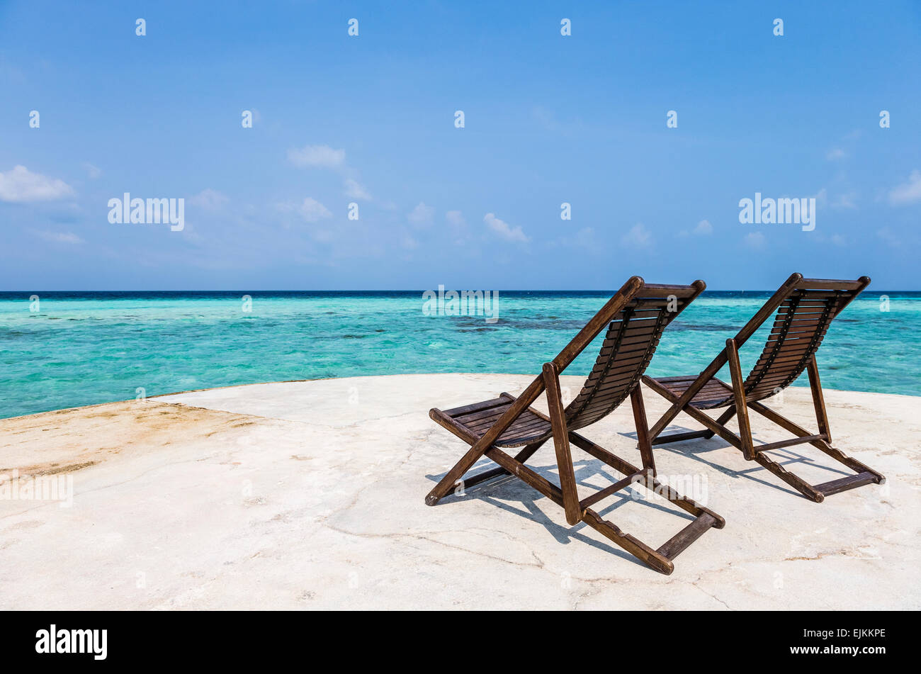 Two deck chairs looking out to sea on a sea defence groin at the island ...