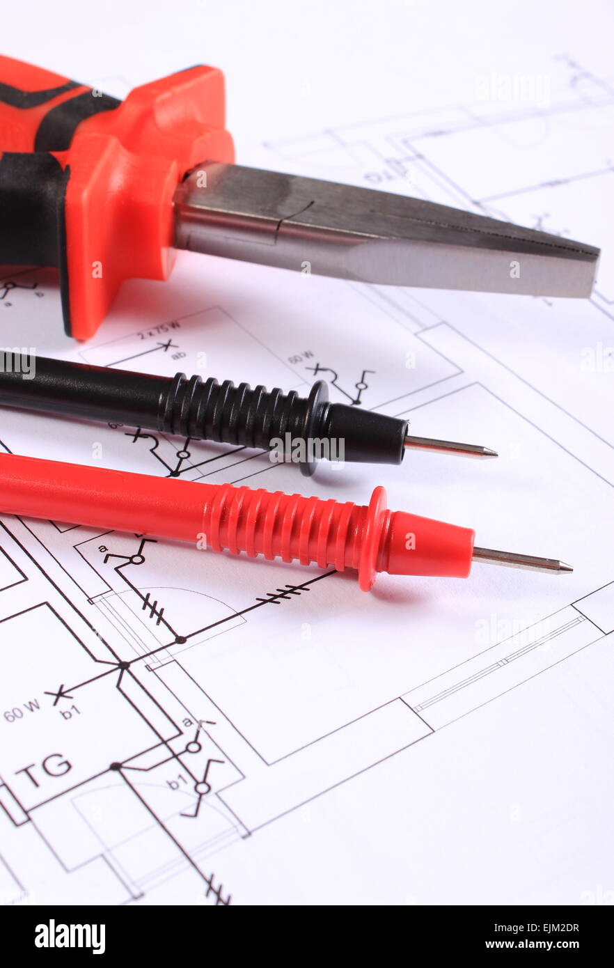 Cables of multimeter and metal pliers lying on construction drawings of ...