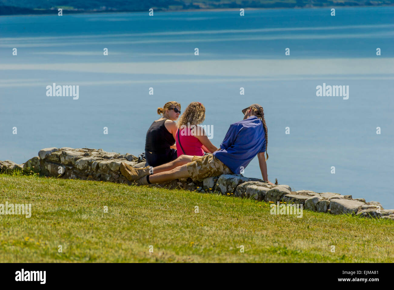 Three young people sunbathing at Criccieth Castle, North Wales, Gwynedd ...
