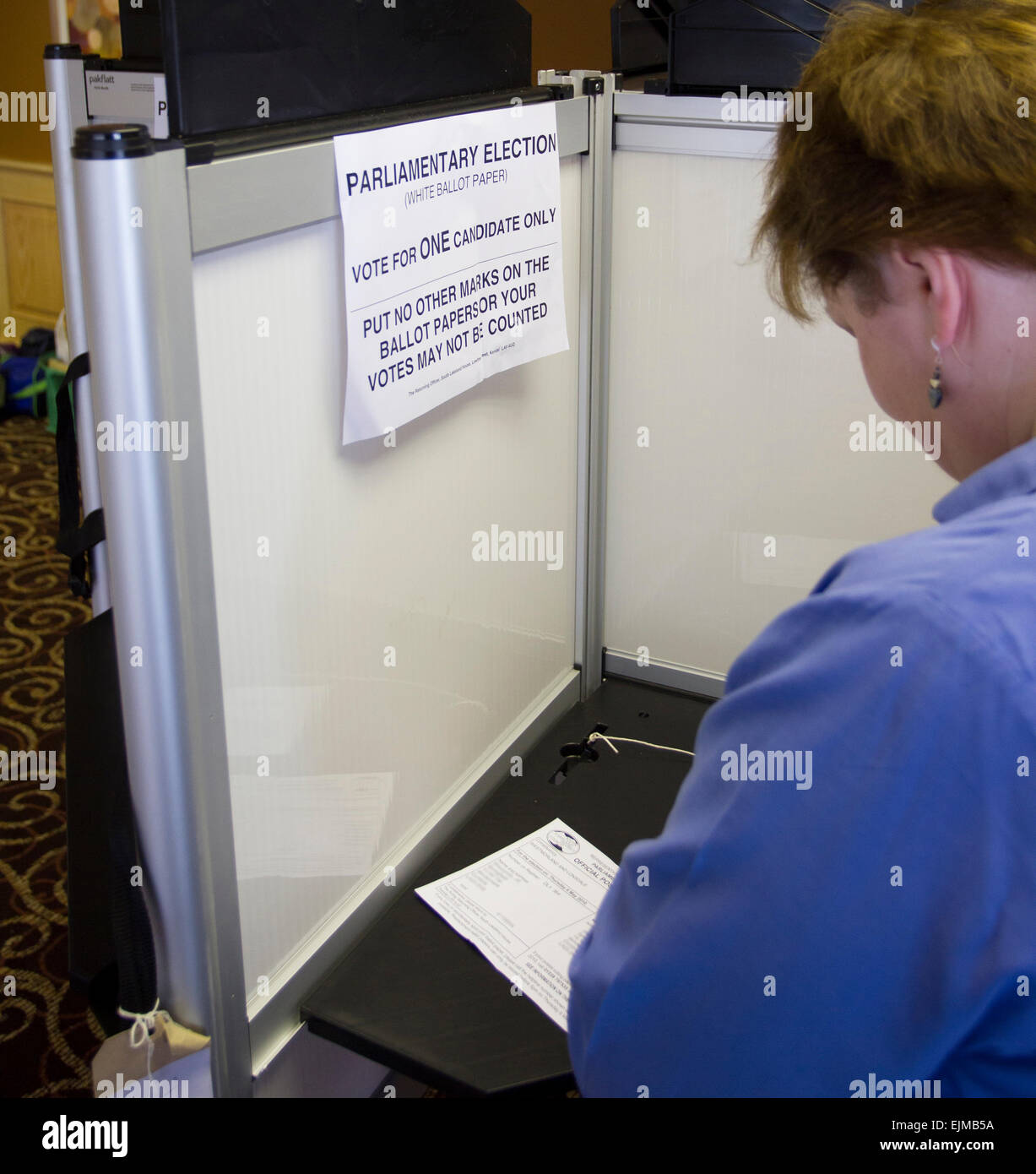 female voter casting her vote by marking ballot paper with cross at ...
