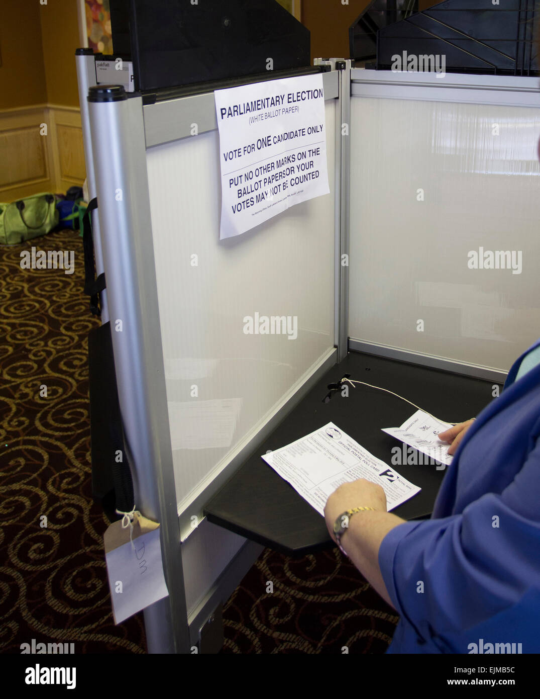 female voter casting her vote by marking ballot paper with cross at ...