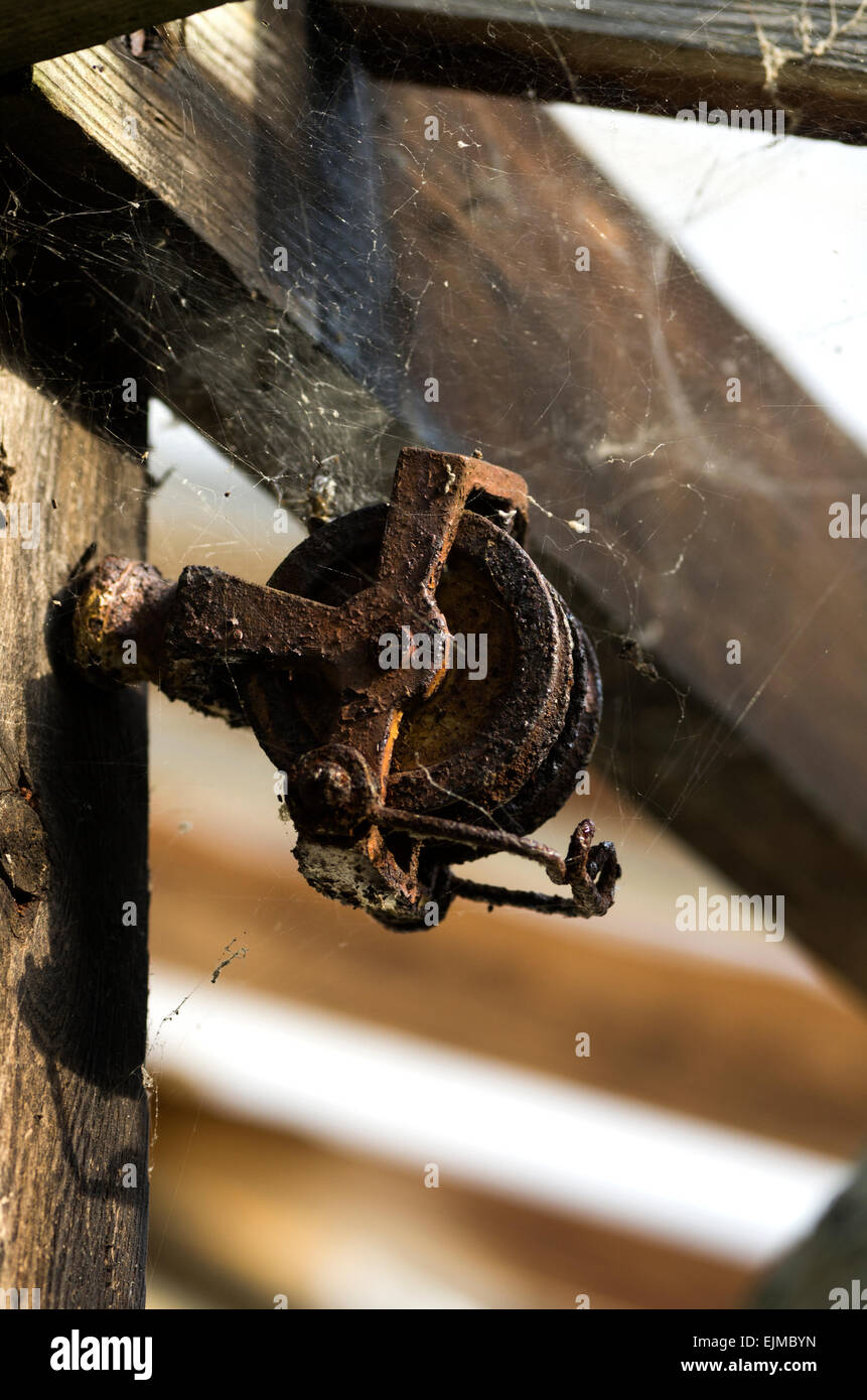 Rusty pulley in autumn sunlight with wooden beams and sunlit wood in ...