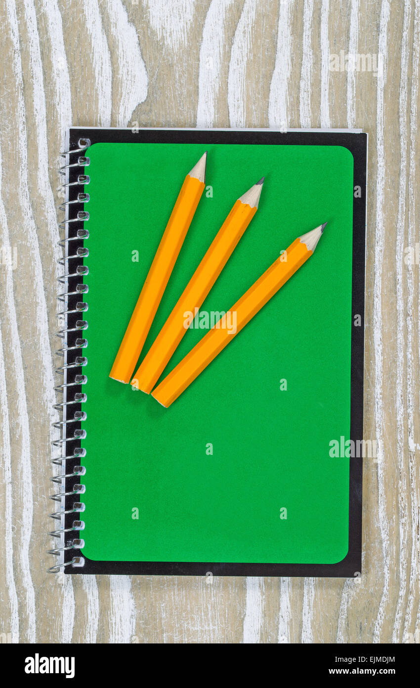 Office desktop with three pencils on top of a notepad with aged white ...