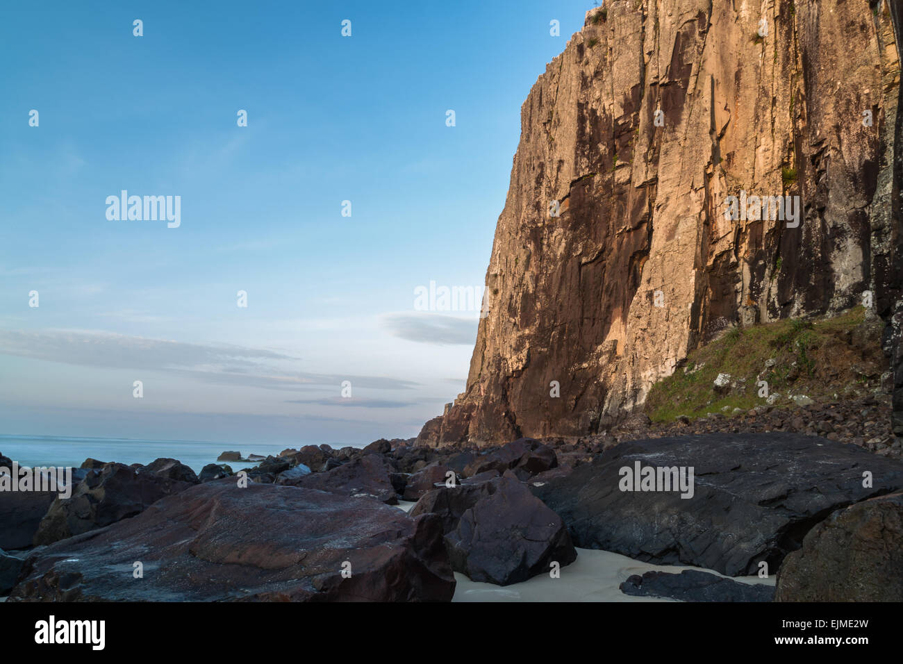 Red sunlight on rock wall and gray rocks at the beach during the ...