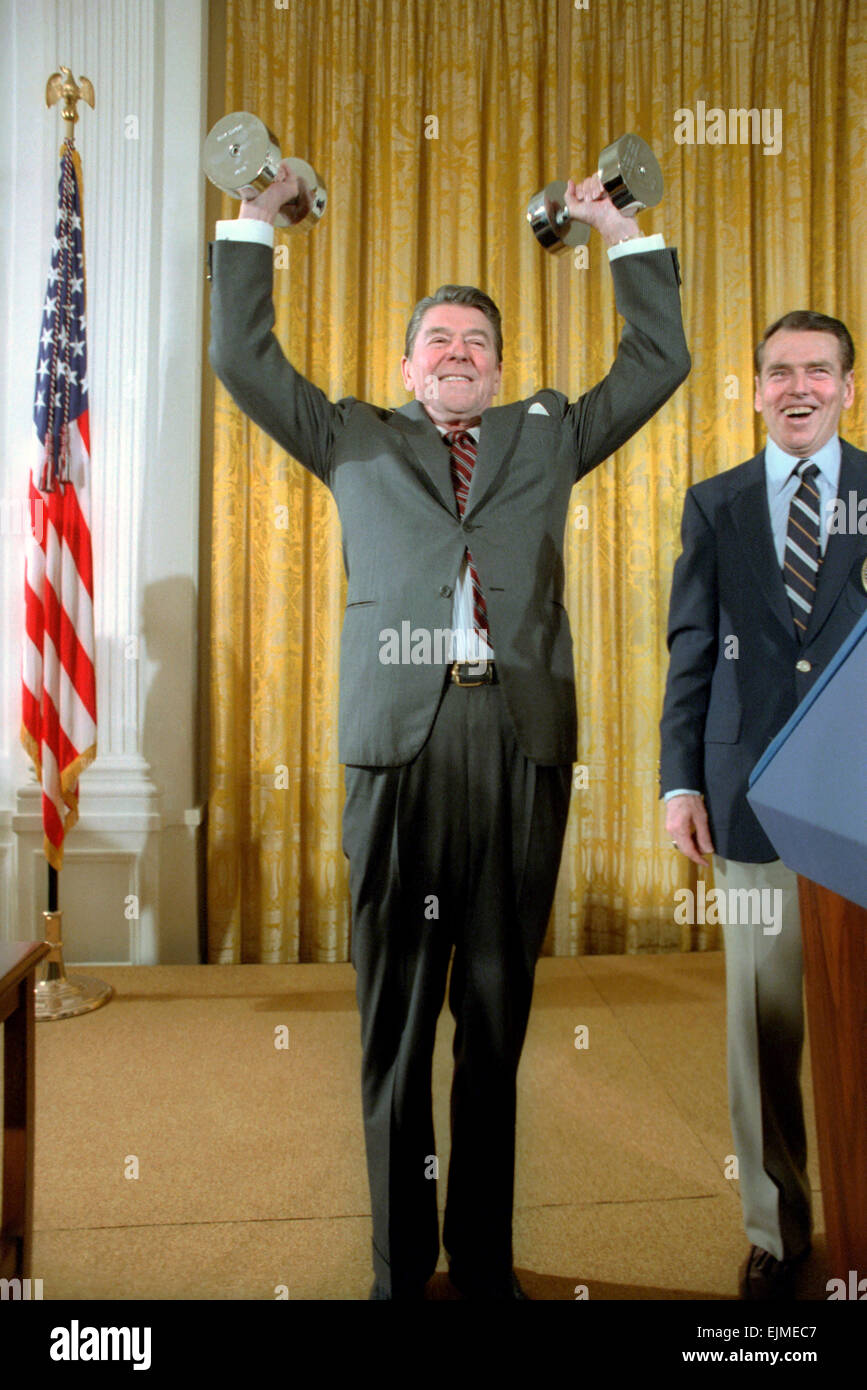 US President Ronald Reagan lifts weight with George Allen looking on ...