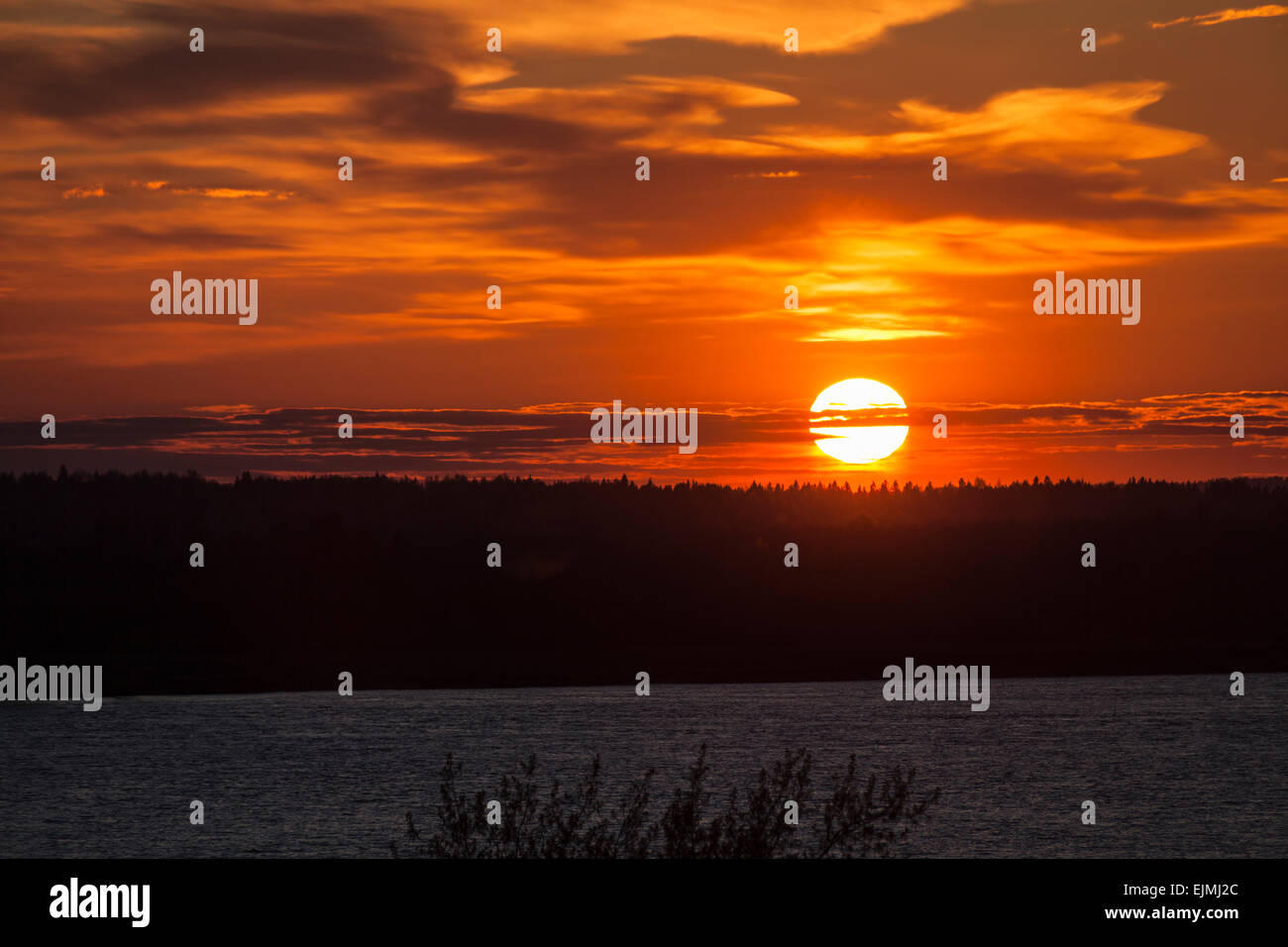 Colourful and dramatic sunset with large yellow sun setting in an ...