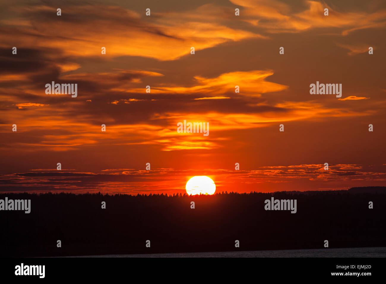 Colourful and dramatic sunset with large yellow sun setting in an ...