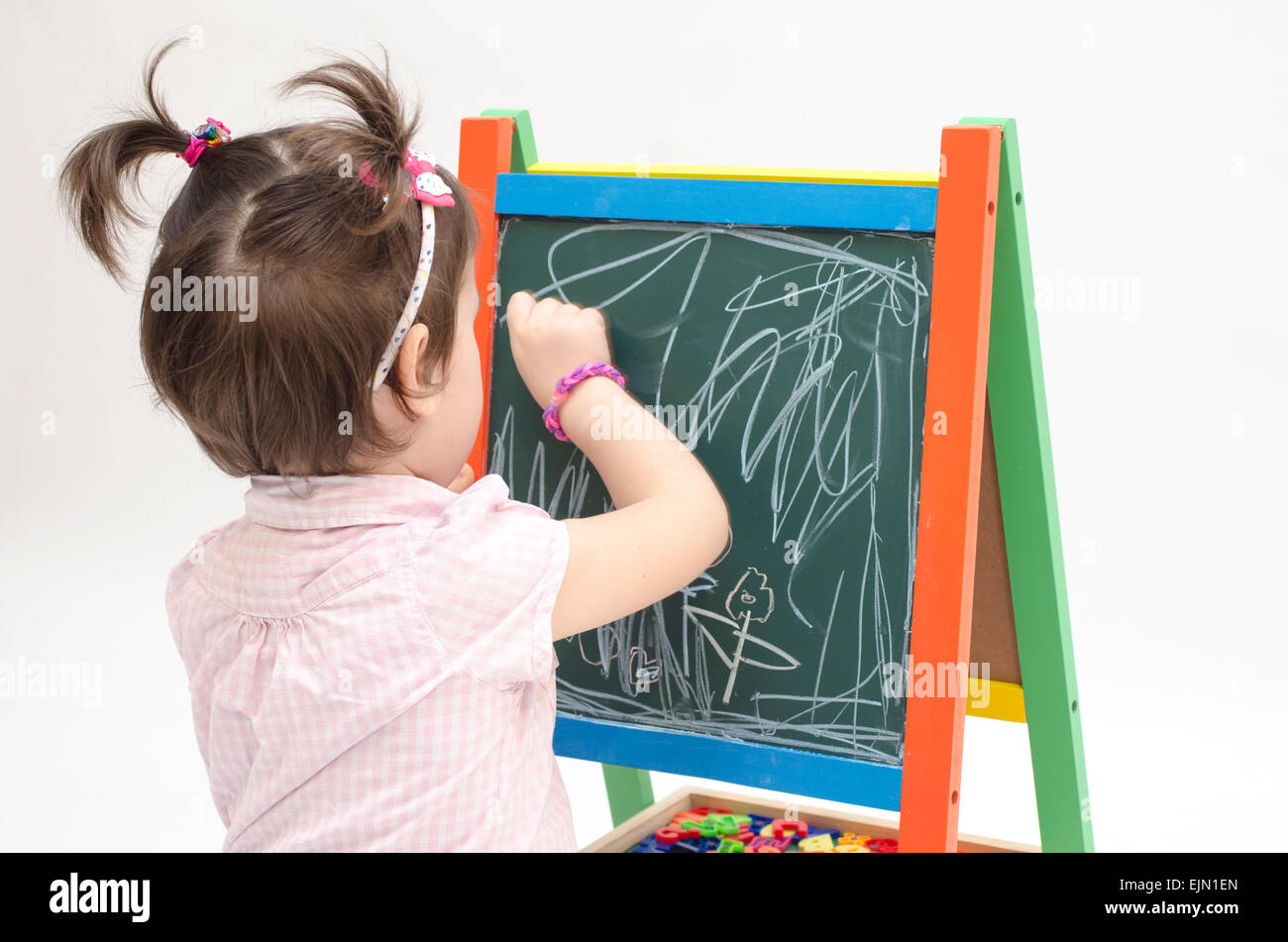 Little girl scratches with chalk on blackboard isolated on white ...