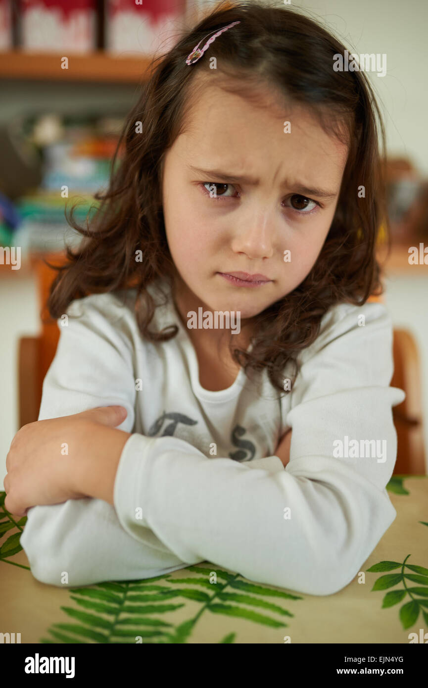 Sulky child of six years sitting at a table Stock Photo - Alamy