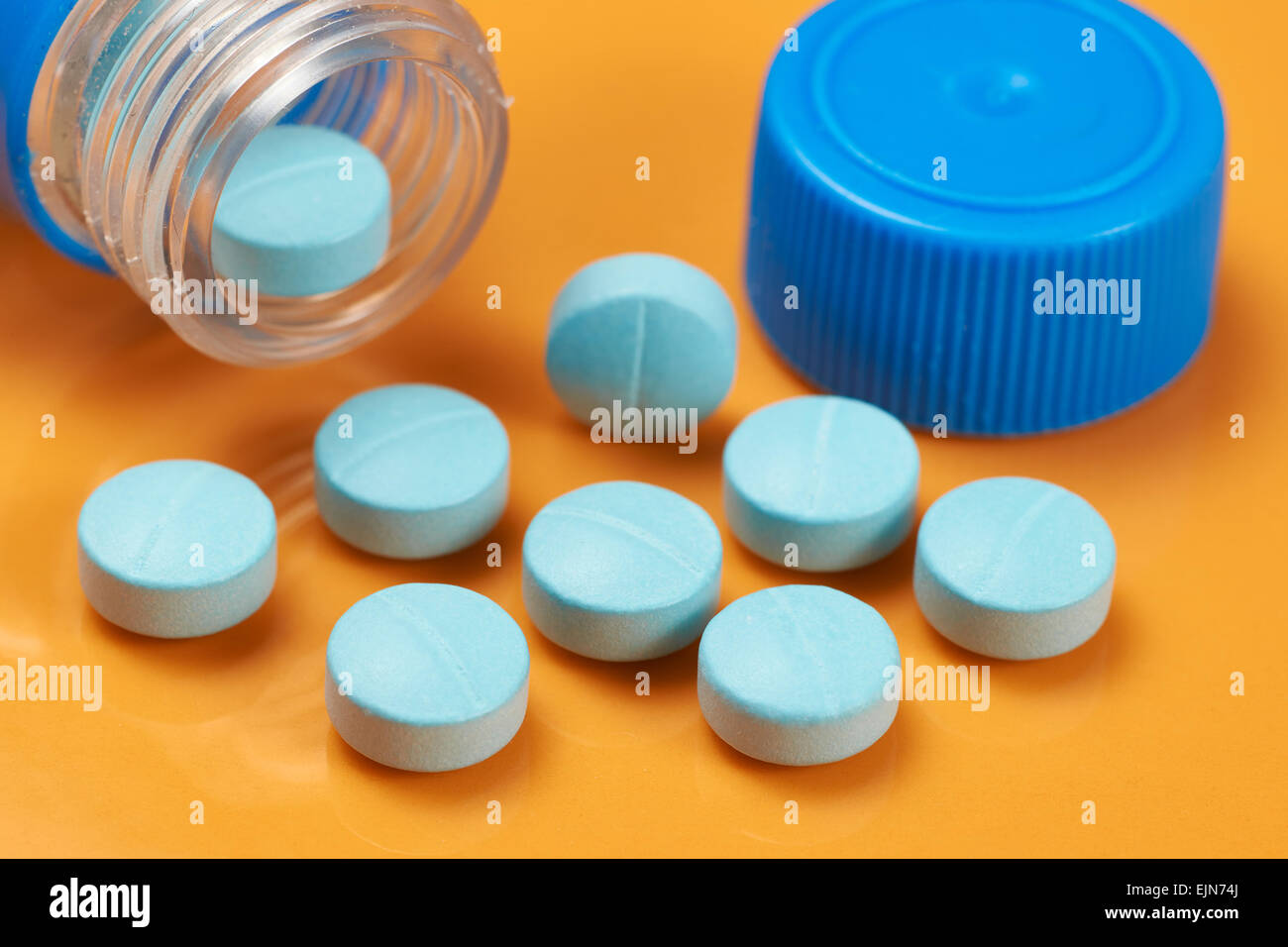 medicinal tablets with blue container and cap on an orange table Stock ...