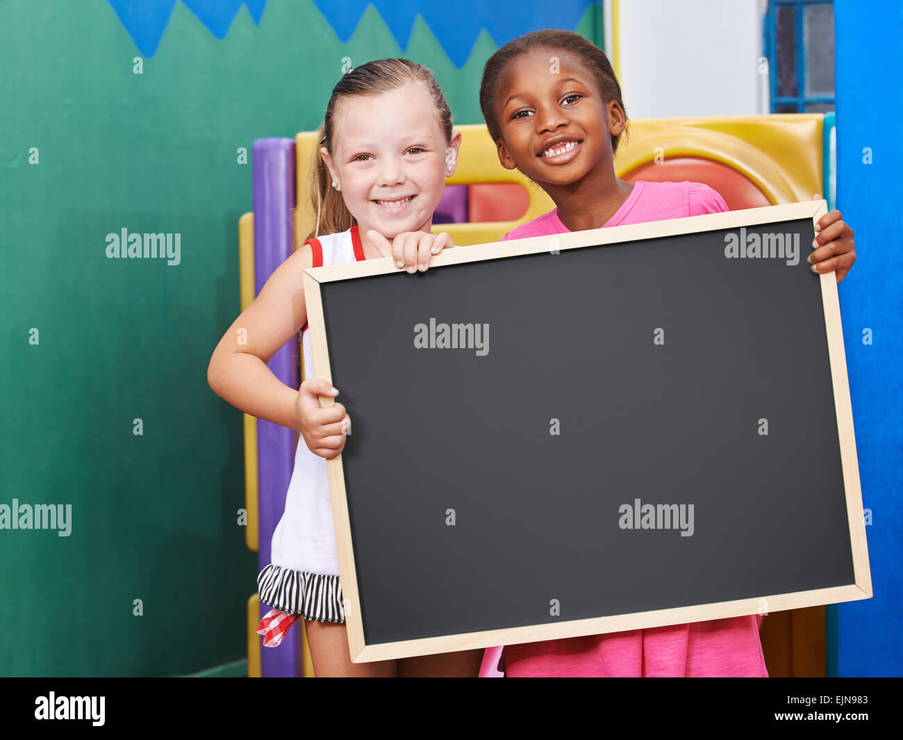 Two happy children holding an empty chalkboard in preschool Stock Photo ...