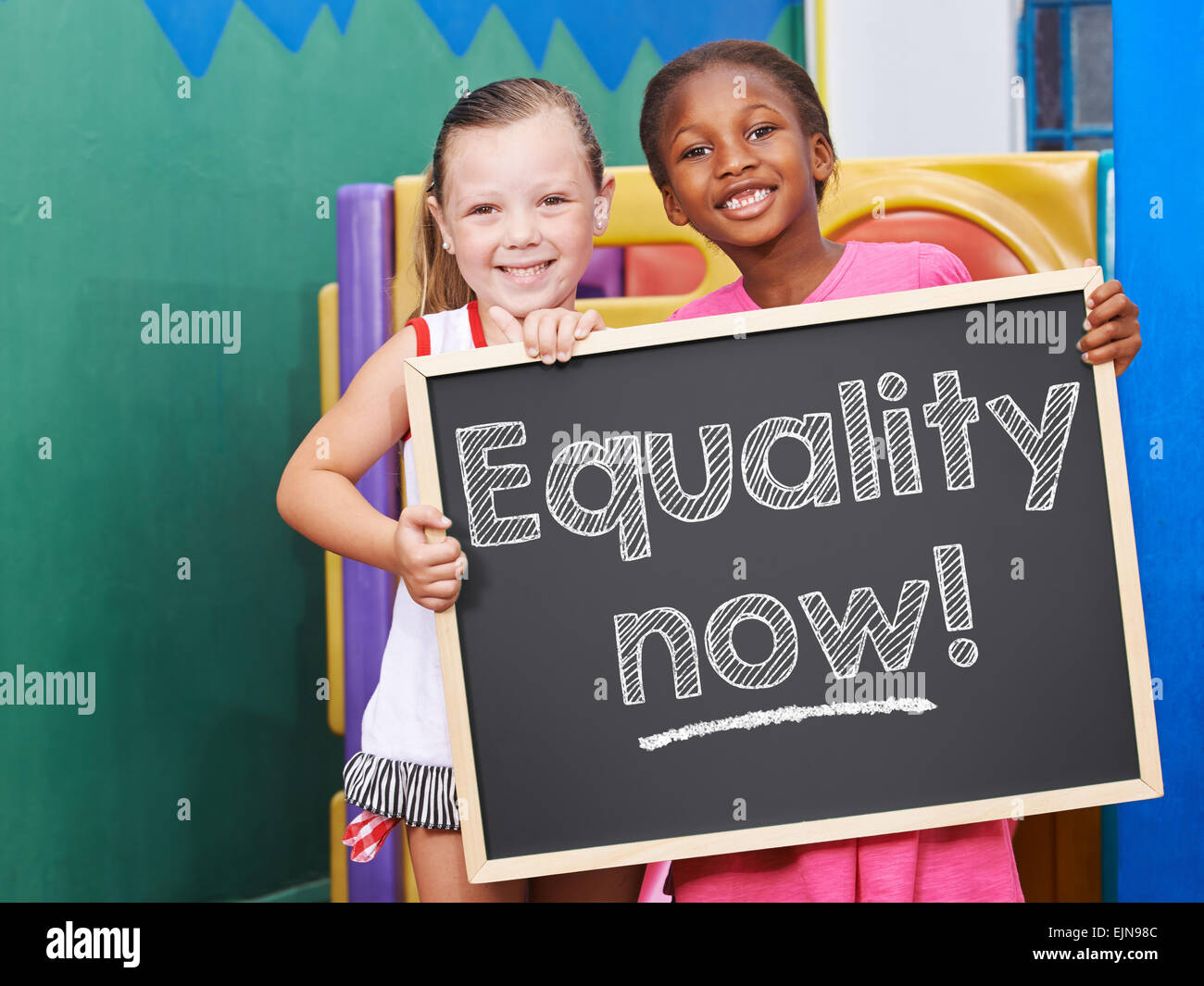 Two happy children demanding "Equality now!" on a blackboard Stock ...