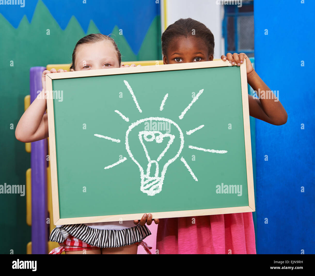 Two children holding a chalkboard with a lightbulb drawn on it Stock ...