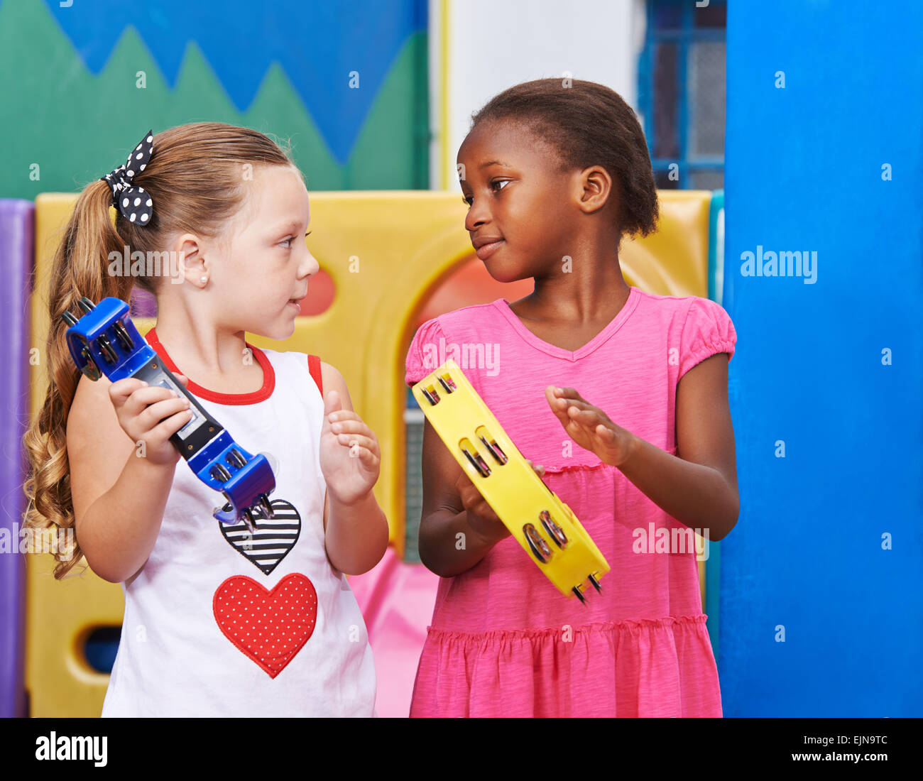 Children playing tambourines in early musical education in kindergarten ...