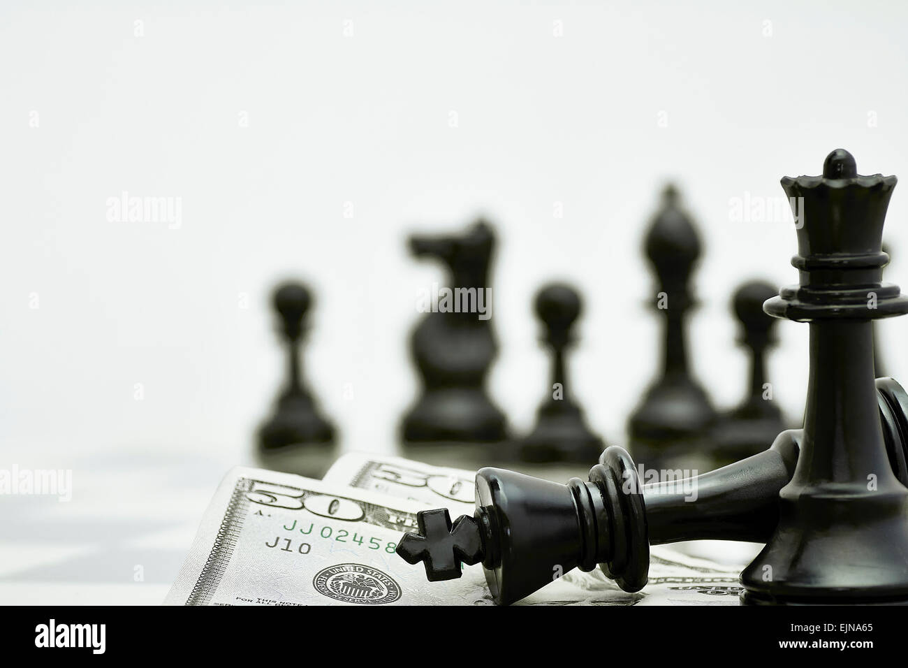 King and queen chess pieces with fifty dollar bills, king laying down ...