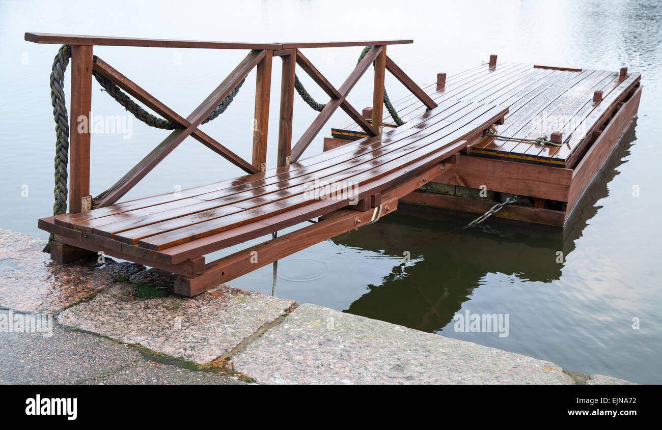 Shining wet wooden floating pier in still lake water, Finland Stock ...