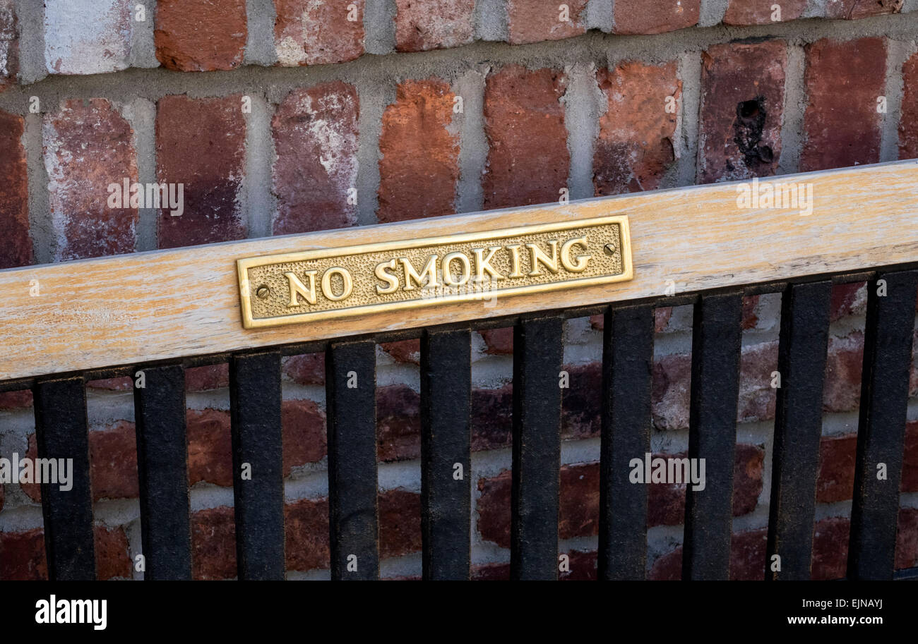 A no smoking sign attached to a wooden bench outside a bar restaurant ...