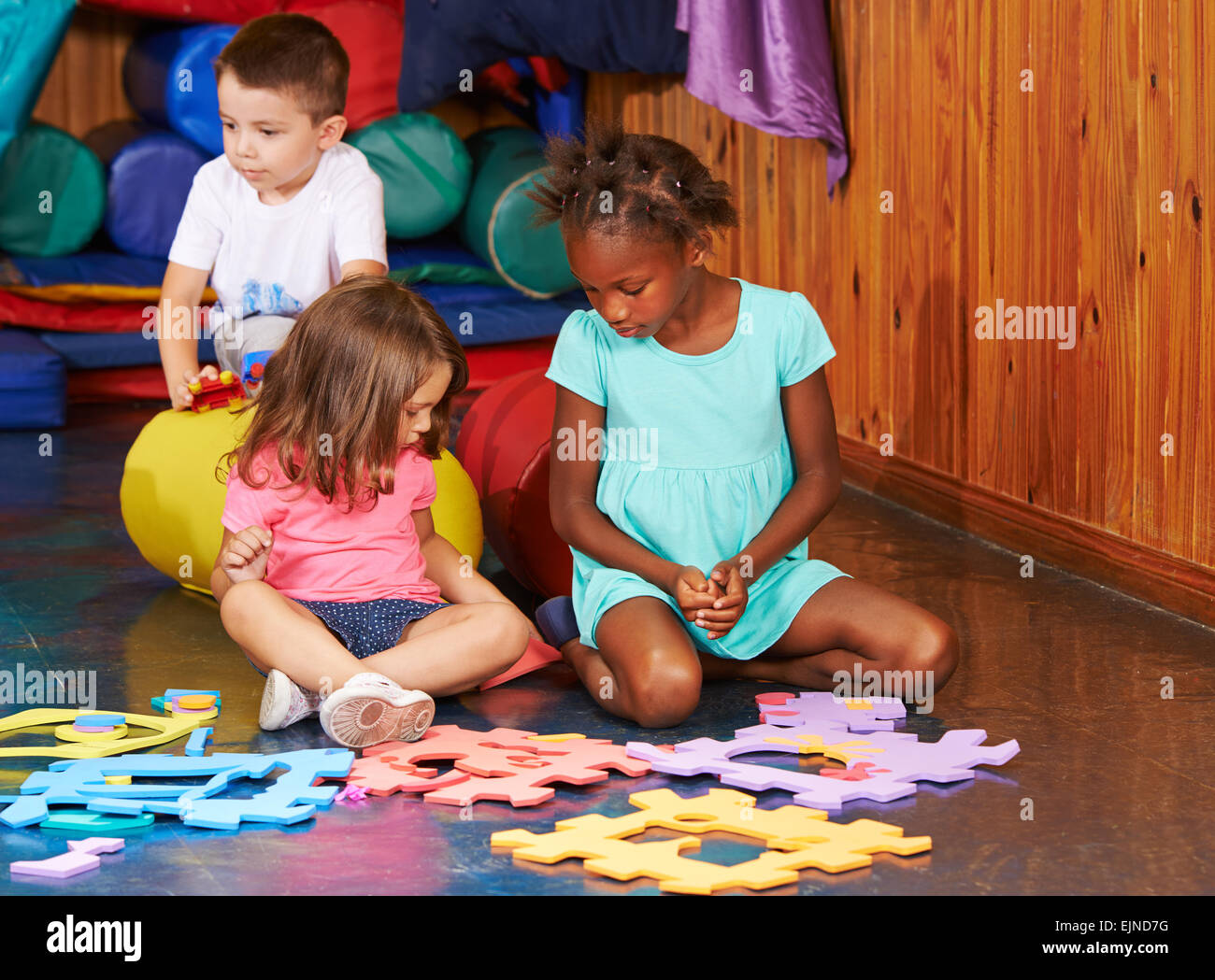 Children playing together with a jigsaw puzzle in kindergarten Stock ...