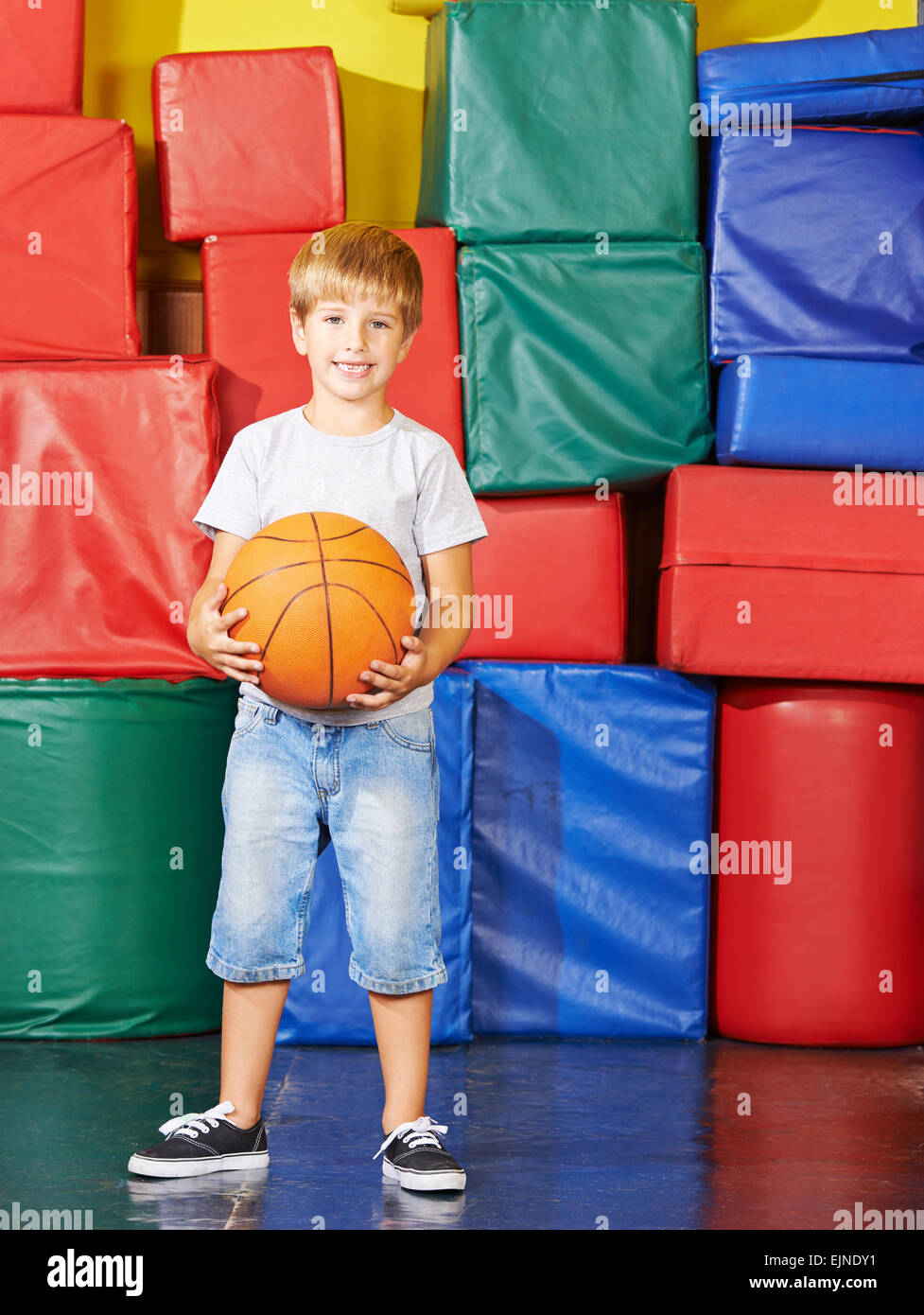 Smiling boy standing with basketball in gym of preschool Stock Photo ...