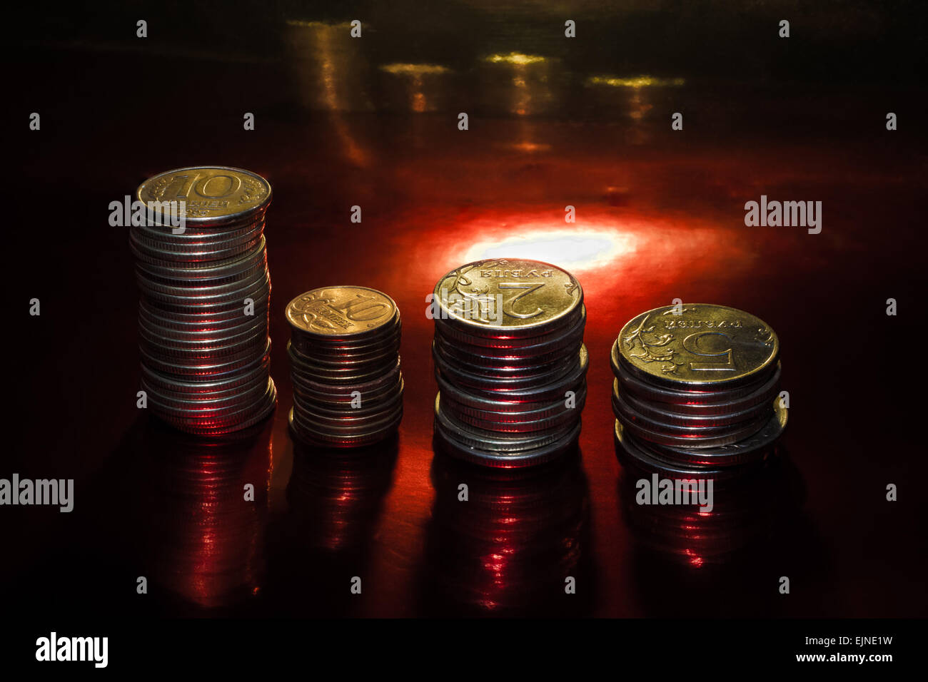 fstack of coins on a dark red background with mirror reflection Stock ...