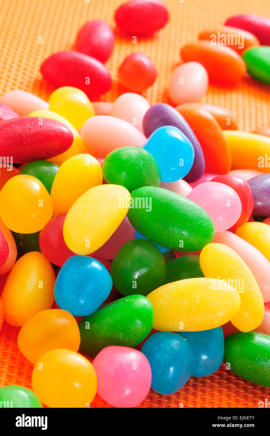 a pile of jelly beans of different colors on an orange woven background ...