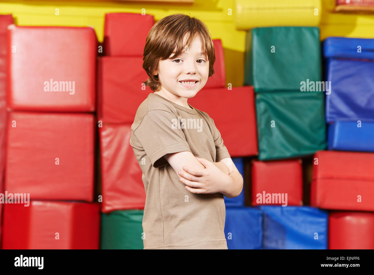Happy kid with his arms crossed standing in gym of kindergarten Stock ...