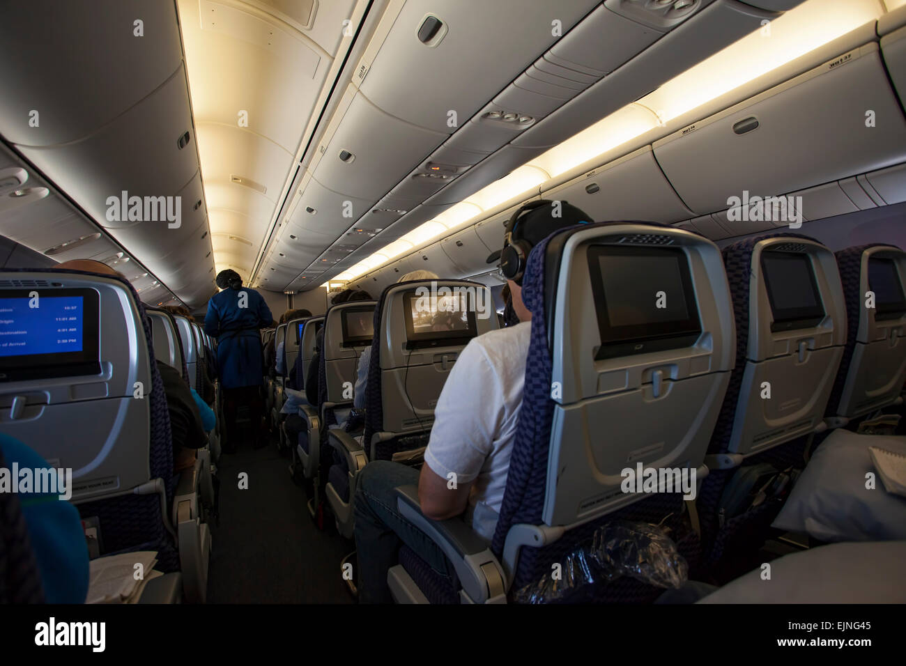 Passengers in flight international flight watch movies Stock Photo - Alamy