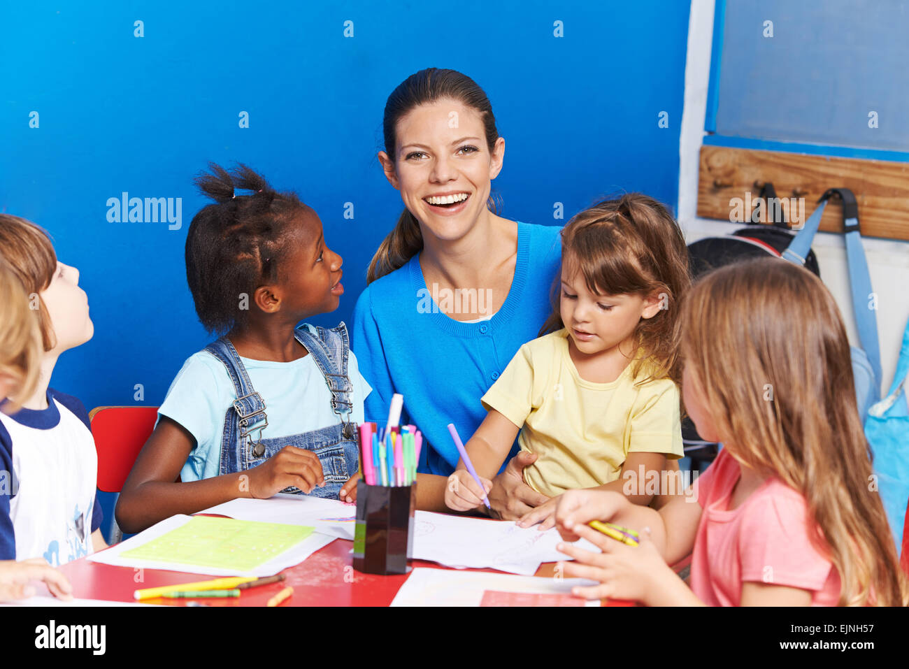 Happy nursery teacher with children painting in a kindergarten Stock ...