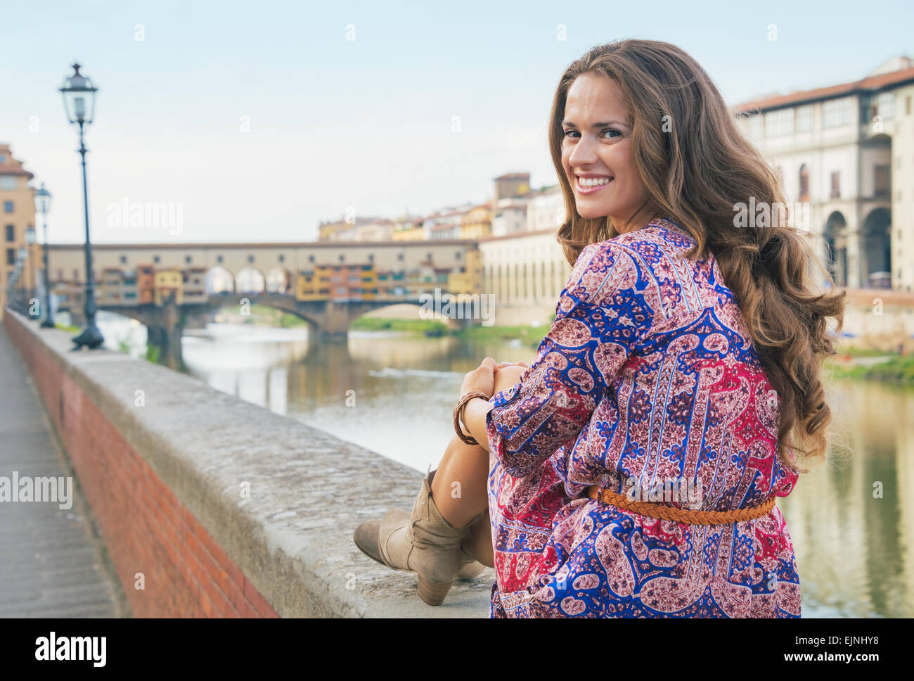Happy young woman sitting near ponte vecchio in florence, italy Stock ...