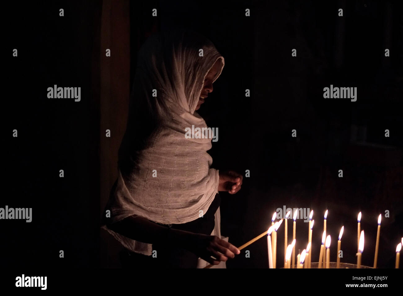 An Ethiopian Orthodox Christian pilgrim lights candles inside the ...