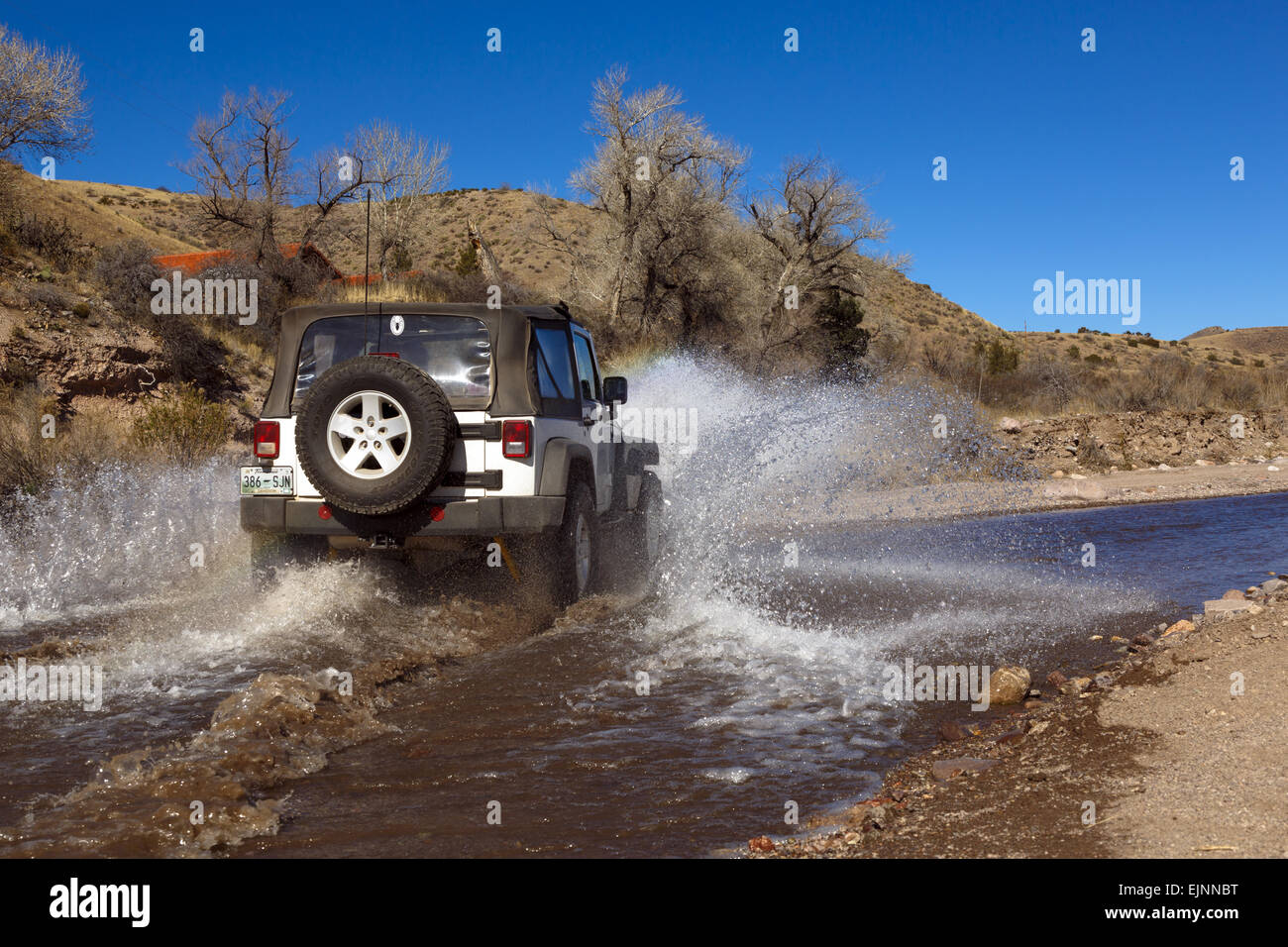 Jeep creating spray driving through water along Alamosa Creek ...