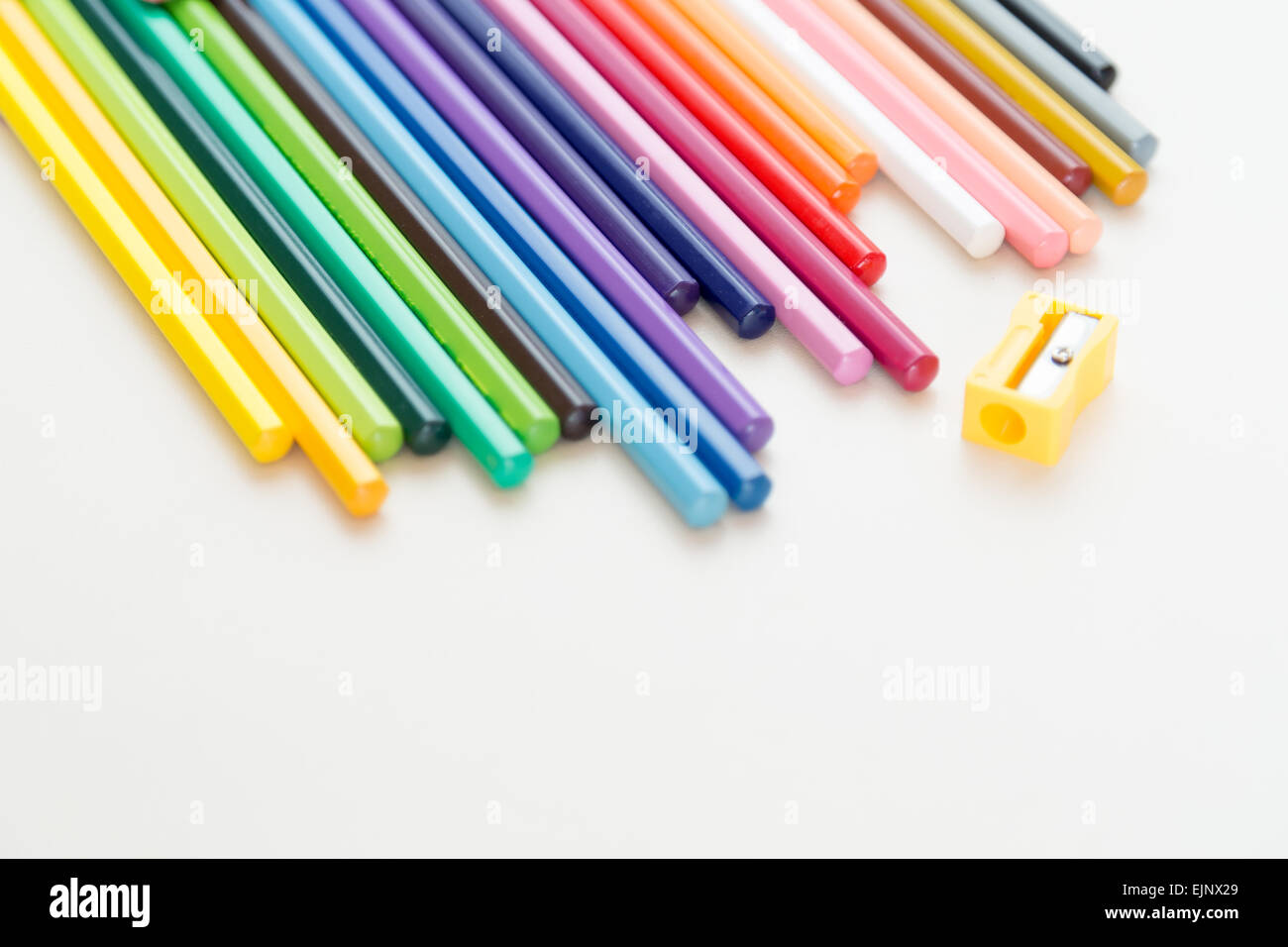 Colorful pencil crayons and sharpener on white desktop Stock Photo - Alamy