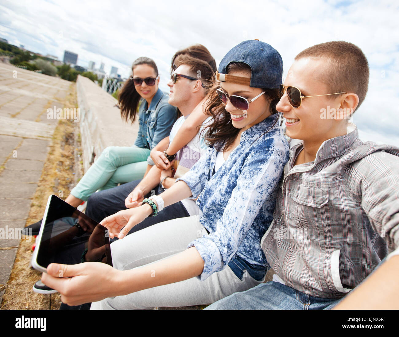 group of teenagers looking at tablet pc Stock Photo - Alamy