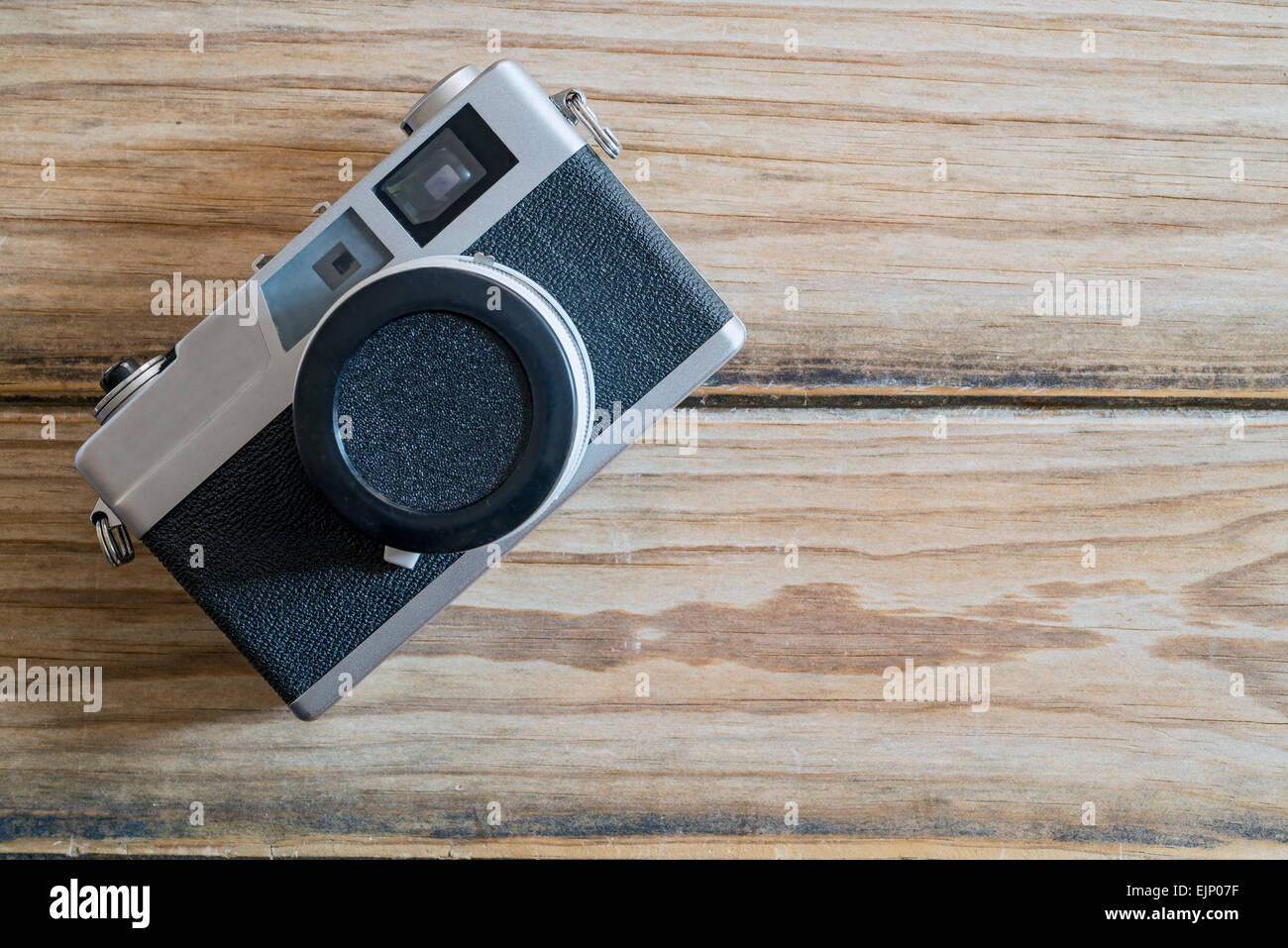 An old black-and-silver analog film camera positioned on its back on a ...