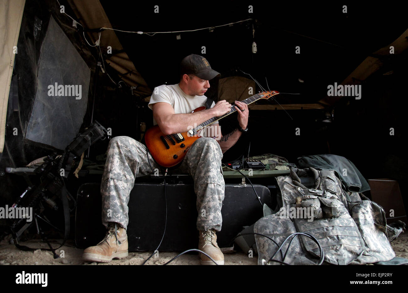 A U.S. Army Soldier uses his down time to practice playing his guitar ...