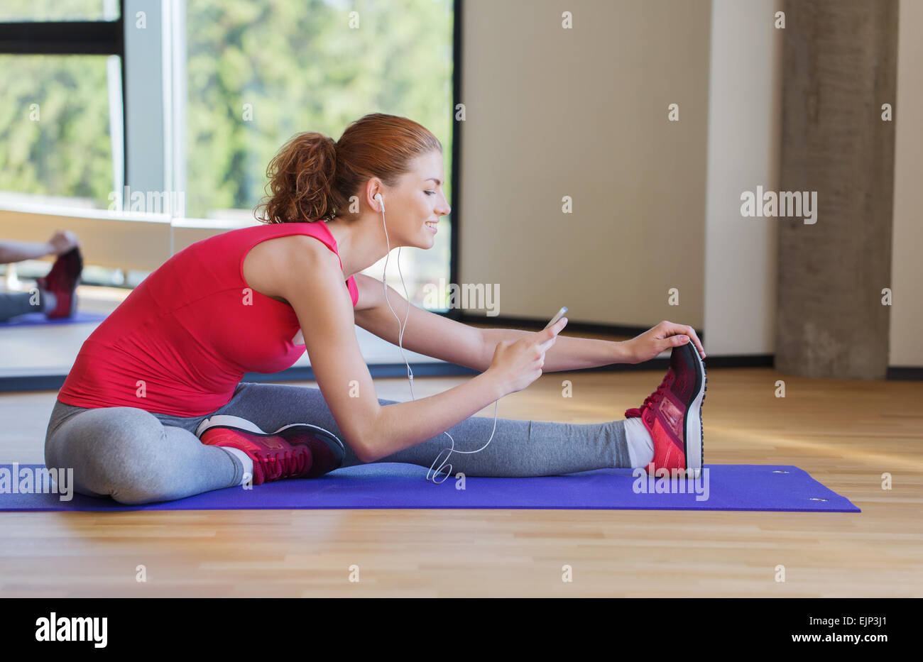 smiling woman stretching on mat in the gym Stock Photo - Alamy