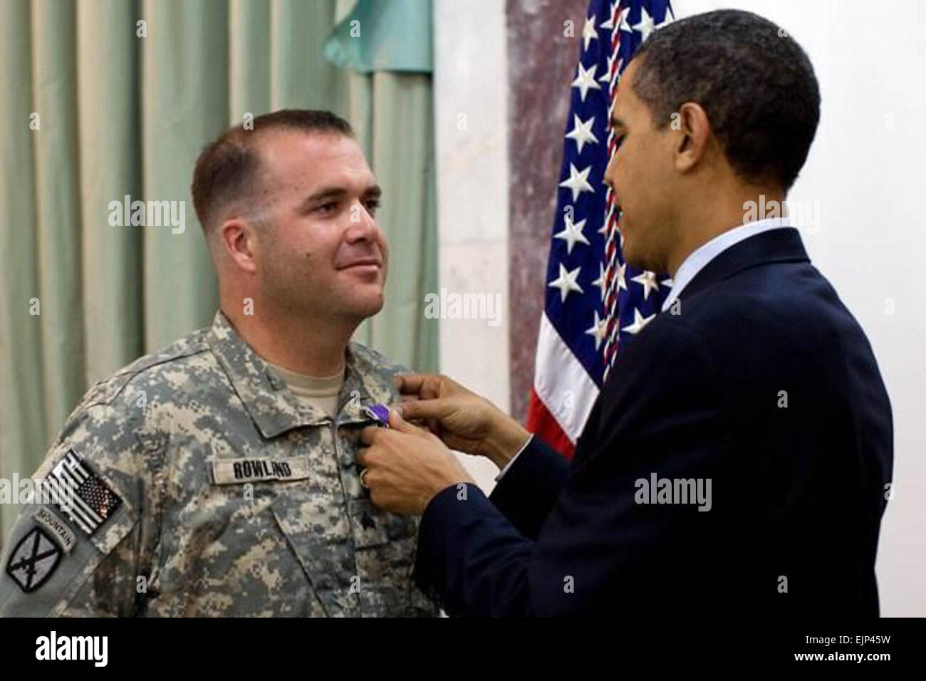President Barack Obama awards the Purple Heart to a soldier standing at ...