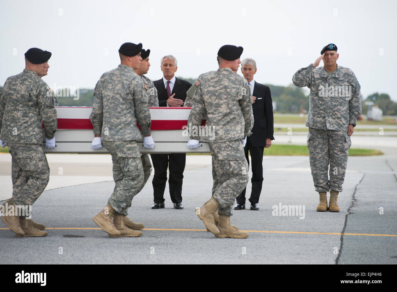 Secretary of Defense Chuck Hagel renders honors as a carry team carries ...