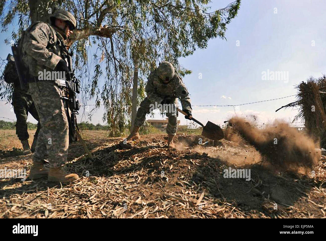 A U.S. Army soldier uses a shovel to dig and inspect a suspected ...