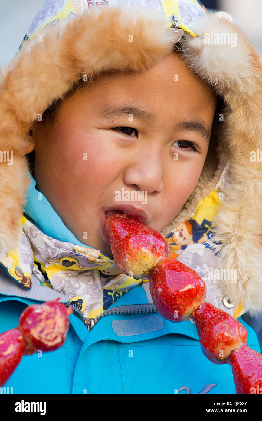 China, Heilongjiang Province, Harbin, winter, boy eating frozen fruit ...