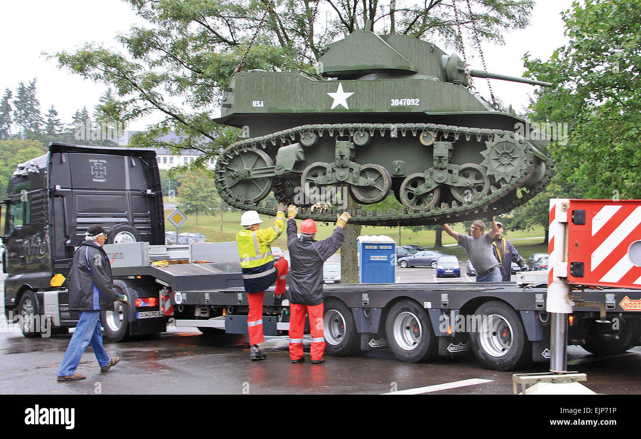 Workers load a World War II-era tank onto a truck in preparation for ...