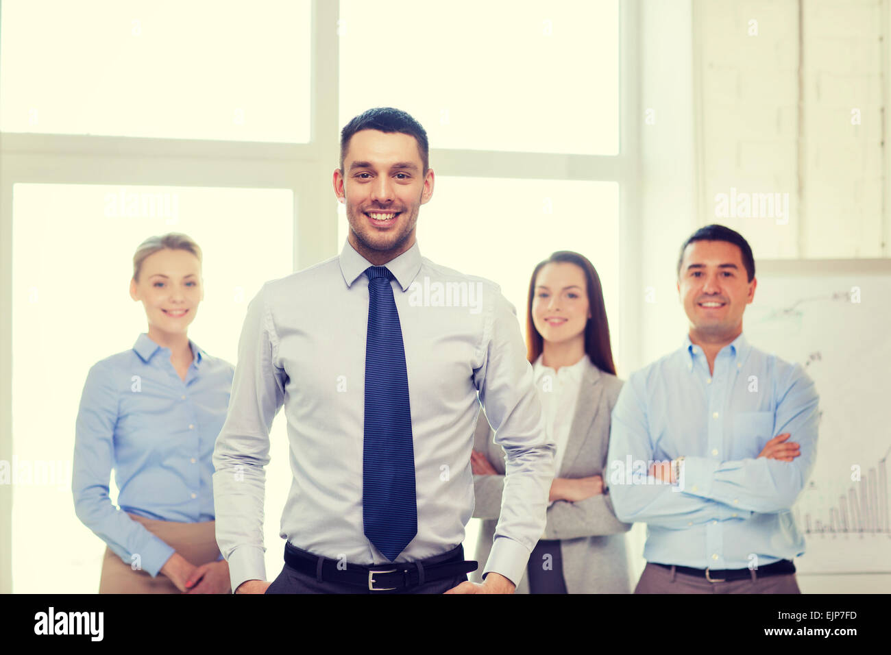 smiling businessman in office with team on back Stock Photo - Alamy