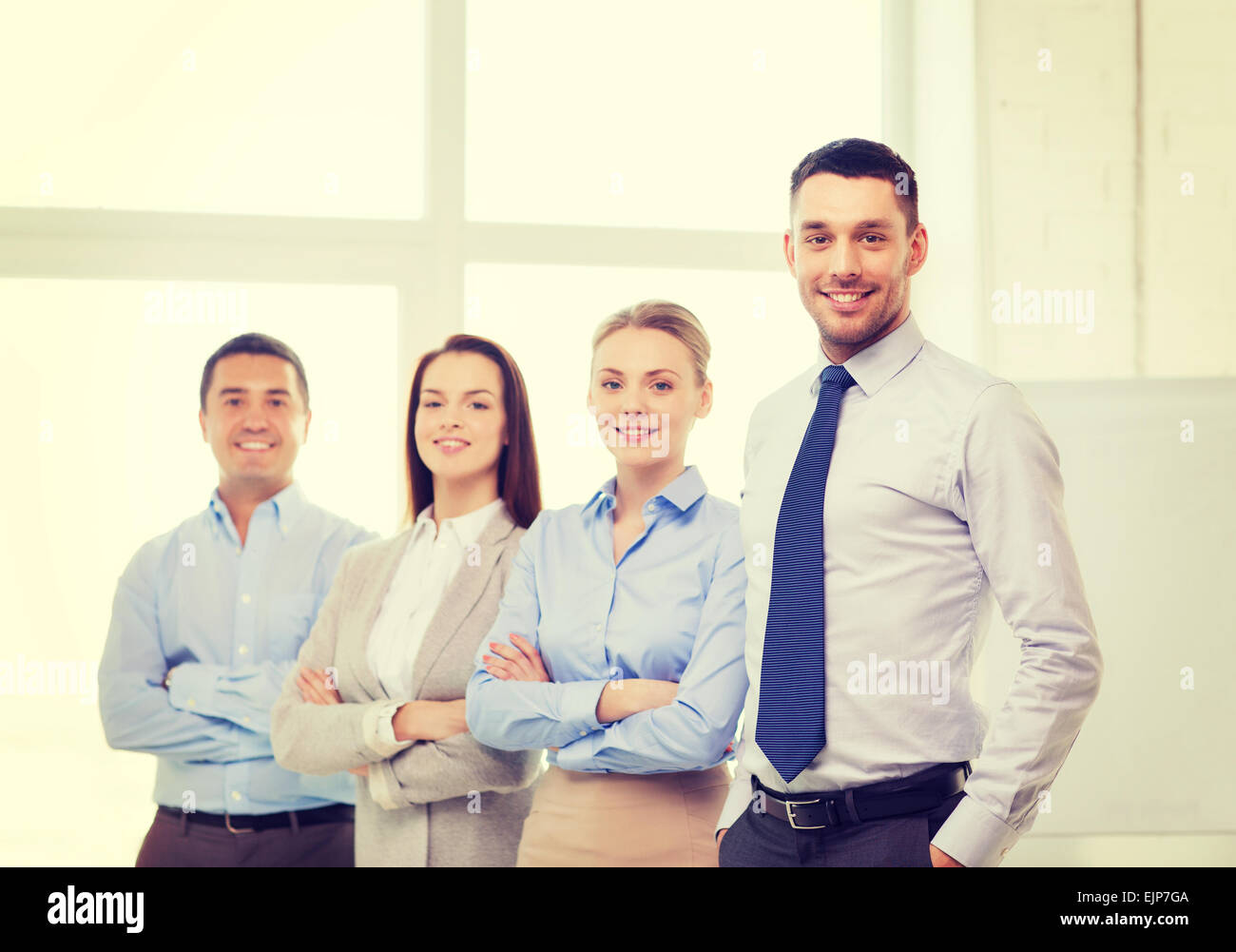 smiling businessman in office with team on back Stock Photo - Alamy