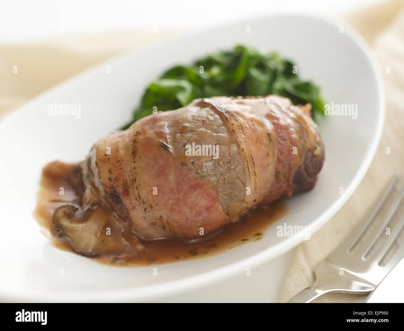 Stuffed Beef with bacon parcel gravy and greens on plate Stock Photo ...
